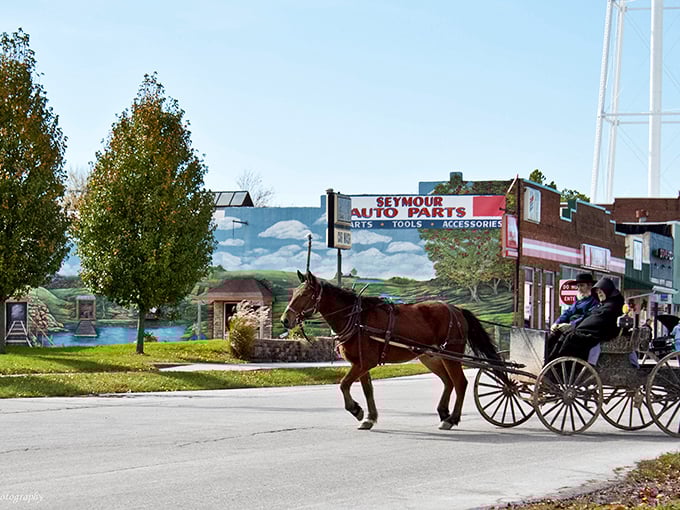 Where modern meets tradition – an Amish buggy rolls past Seymour Auto Parts, creating a visual timeline of transportation spanning two centuries in a single frame.