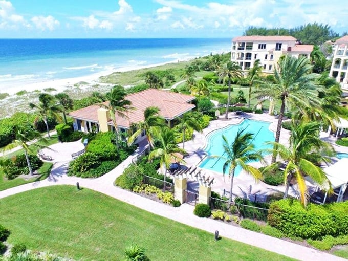 Beach living perfected: Palm trees standing guard over pristine sands and azure waters—the daily "terrible view" Longboat Key residents somehow endure.