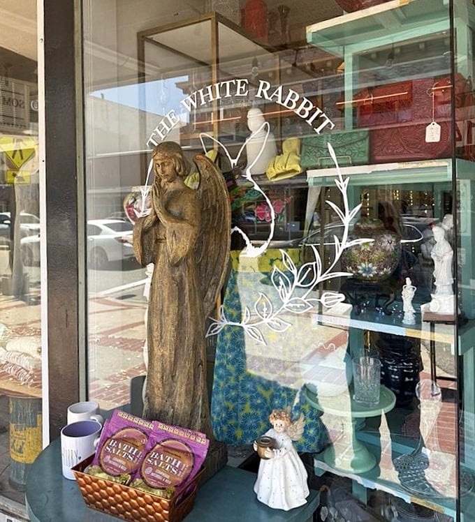This window display could double as a film set—where else would you find an elegant angel statue keeping watch over delicate figurines and colorful textiles?