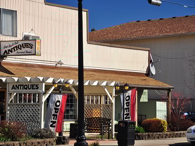 The Pack Rat Antiques welcomes treasure hunters with its inviting porch and fluttering "OPEN" flags – your first clue that discoveries await inside.