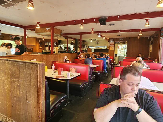 Red vinyl booths worn to comfortable perfection, wood-paneled walls, and the hum of satisfied conversation – this is diner paradise in its purest form.