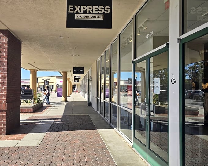 Coach's storefront beckons with promises of luxury at less painful prices. That bench isn't just for tired shoppers—it's for partners contemplating their financial futures.
