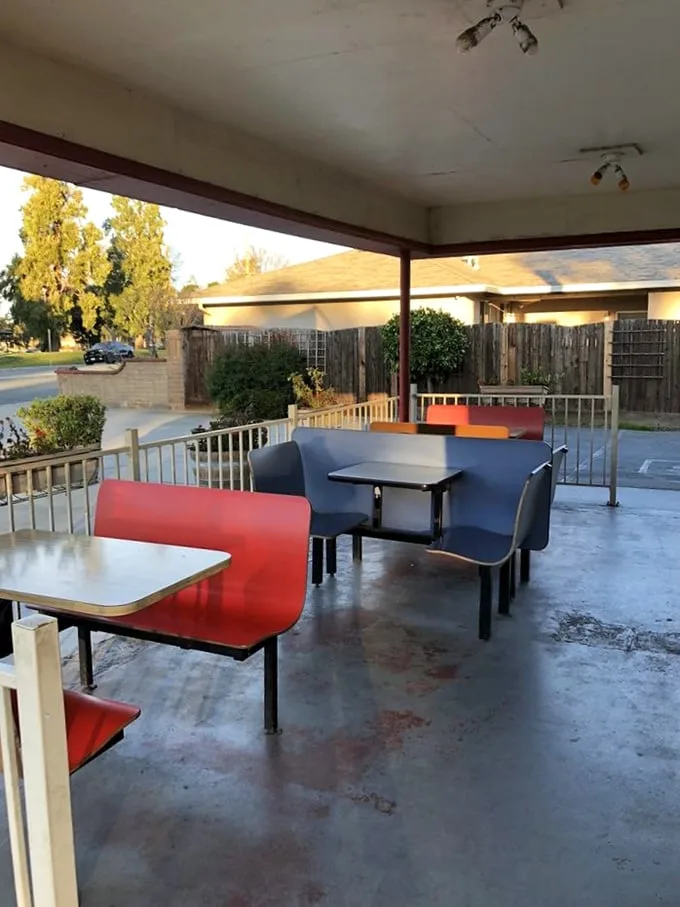 Red and blue bench seating under a simple awning—where conversations flow as freely as the ketchup and nostalgia comes standard with every meal.