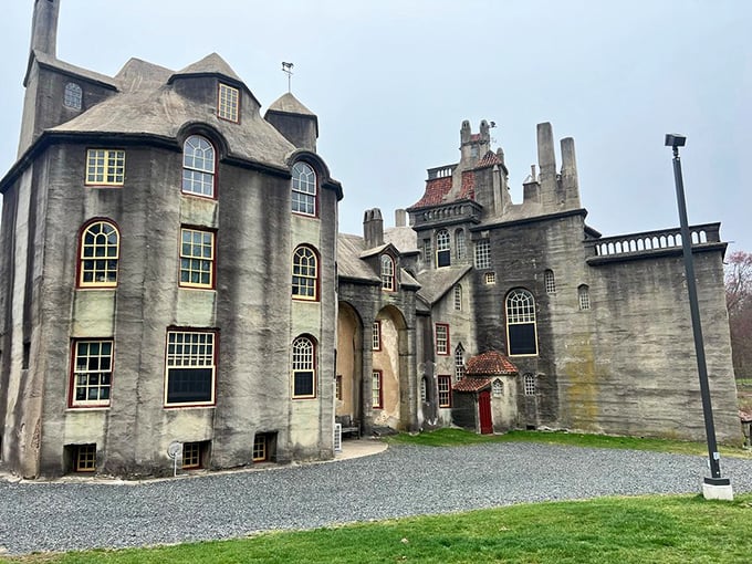 The castle's imposing façade reveals its eccentric personality—windows of all shapes and sizes scattered across concrete walls like an architectural jazz improvisation.