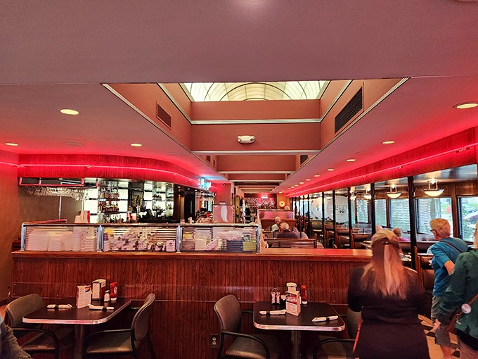 Step inside and the warm red neon glow bathes everything in a rosy hue, making even Tuesday morning coffee feel like a special occasion.