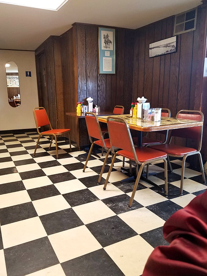Classic diner aesthetics at their finest – wood paneling, checkered floors, and orange chairs that have cradled countless satisfied customers through decades of delicious meals.
