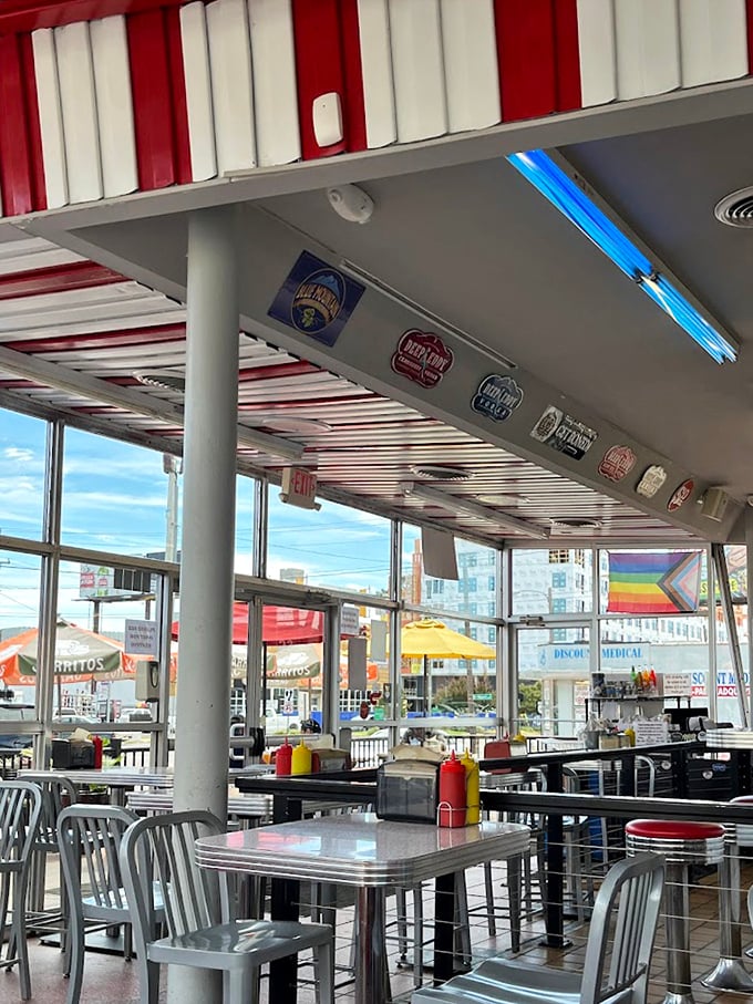 Classic Americana with a modern twist—red and white stripes overhead, beer signs aplenty, and those unmistakable diner-style metal chairs.