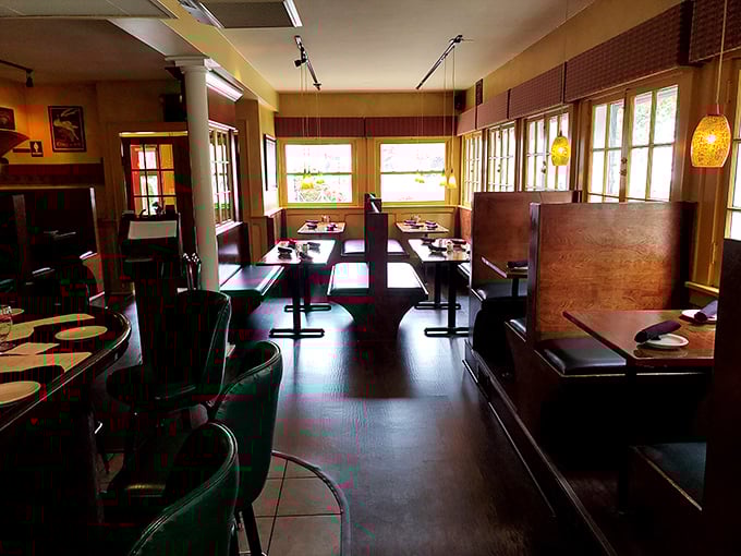 Inside, warm amber lighting bathes wooden booths and emerald bar chairs in a golden glow that whispers, "Stay awhile. Order seconds."