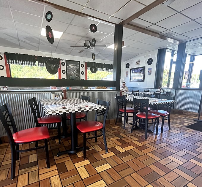 Vinyl records suspended from the ceiling like musical planets orbiting those red vinyl seats—a retro galaxy where comfort food is the star.