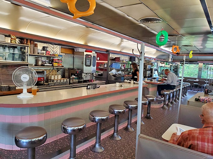 Chrome stools lined up like soldiers at the counter, where regulars perch for their morning ritual. The pink and blue tile work screams "authentic American diner."