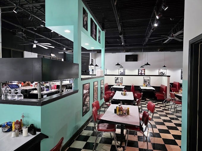 Classic black and white checkered floors meet mint green walls and cherry-red booths—this isn't just decoration, it's a full-blown time machine for your taste buds.