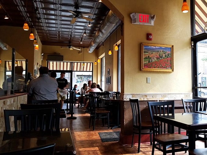 Warm golden walls, exposed ductwork, and that Tuscan landscape painting—this isn't just a restaurant, it's a portal to Italy without the jet lag.