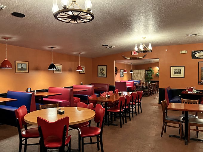 Wagon wheel chandeliers, terracotta walls, and red vinyl chairs—this isn't interior design, it's a time machine to when steakhouses meant business.