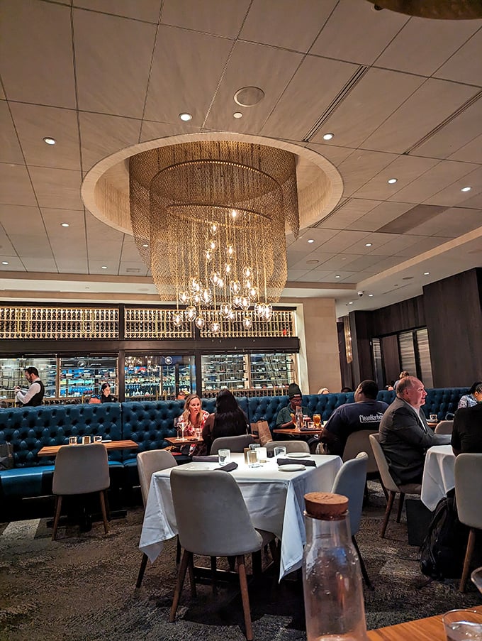 That chandelier isn't compensating for anything—the food stands tall on its own. Elegant lighting, plush blue booths, and white tablecloths set the stage.