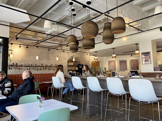 Woven pendant lights hang like artistic cocoons above the counter, where modern design meets meaningful mission in this bright, airy space.