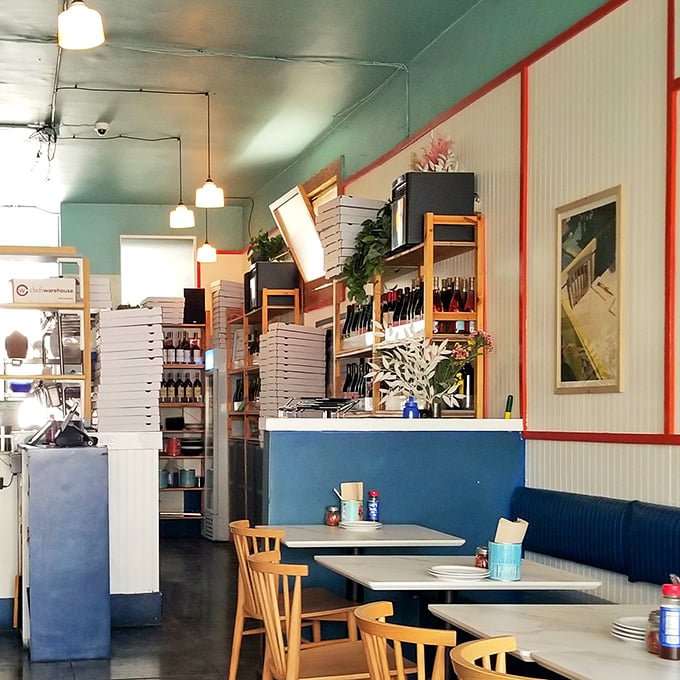 Mint walls, wooden chairs, and stacked pizza boxes create that perfect "we're serious about pizza but not about pretension" vibe.
