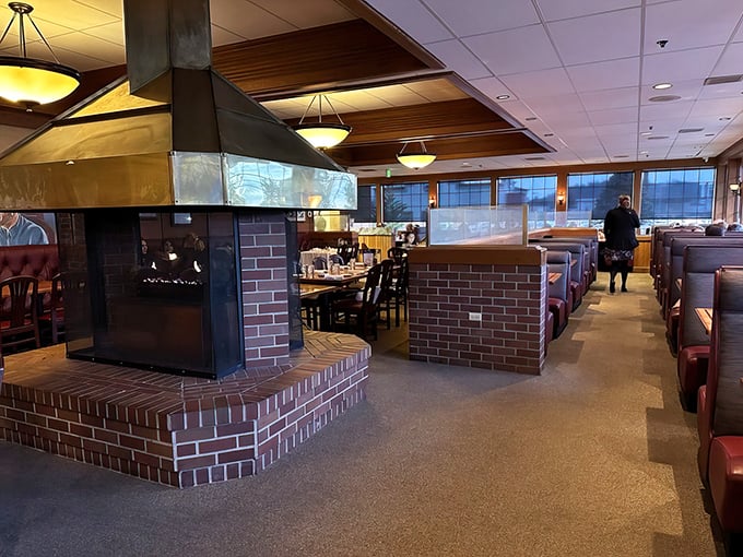 The central fireplace anchors the dining room like a hearth from a bygone era. Those cozy booths have witnessed countless celebrations, first dates, and food comas.