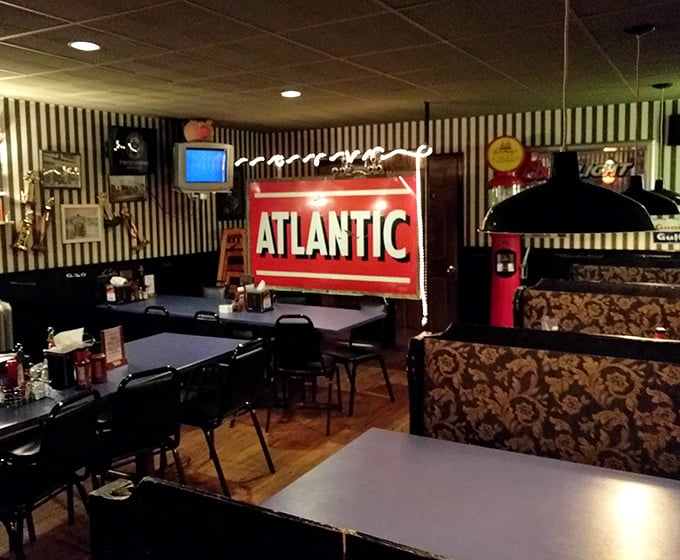 Black and white striped wallpaper meets vintage Americana inside Grumpy's. That glowing Atlantic sign isn't just decoration—it's a promise of roadhouse authenticity.