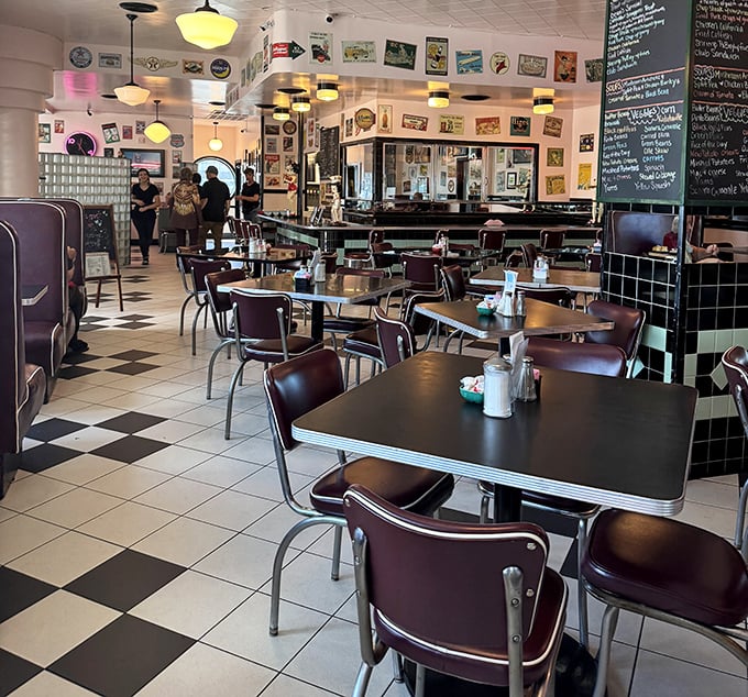 Classic black and white checkered floors, burgundy chairs, and walls adorned with vintage memorabilia—this isn't retro-themed, it's authentically retro.