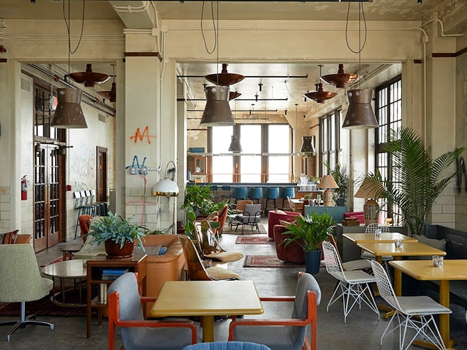 The interior feels like the coolest living room you've never had—vintage furniture, industrial lighting, and plants creating a space that's both hip and homey.