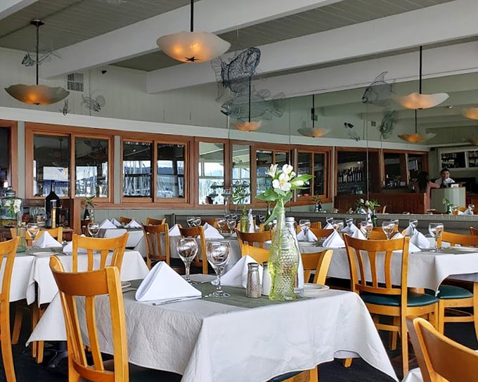 White tablecloths meet honey-colored chairs beneath fishing net decor – oceanside elegance without pretension, where the view competes with what's on your plate.