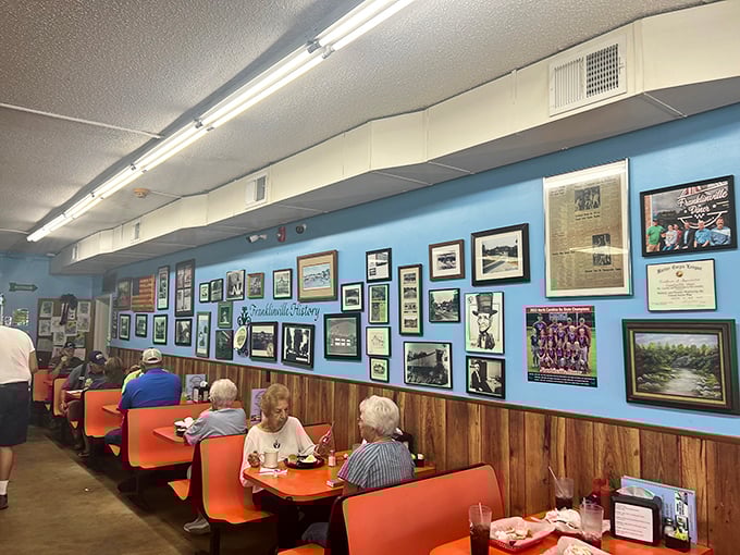 Blue walls adorned with local memories and orange booths filled with regulars – this isn't décor, it's a community scrapbook serving comfort by the plateful.