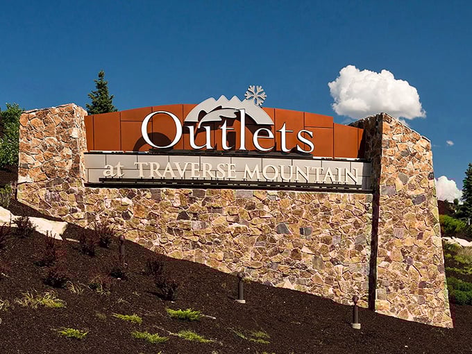 The iconic entrance sign stands against Utah's blue sky, promising retail therapy with mountain-inspired architecture and substantial savings. 