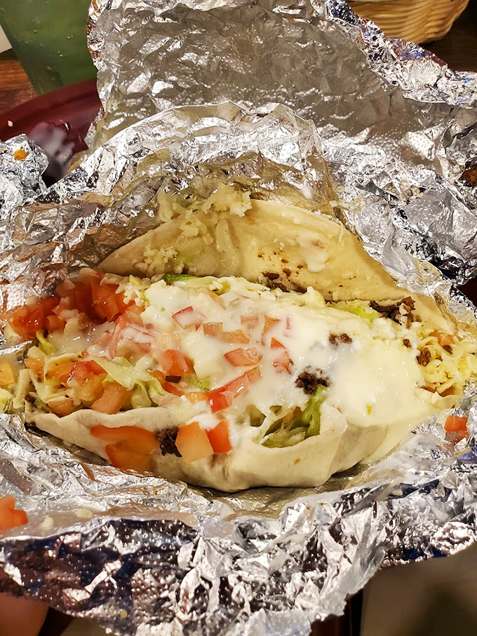 Behold the legendary foil-wrapped burrito in all its glory—cheese melting over perfectly seasoned meat with fresh toppings peeking through.