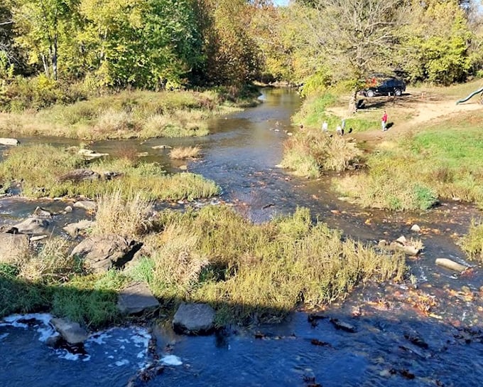 Big Raccoon Creek meanders beneath the bridge, its gentle current and rocky bed creating nature's soundtrack—the original noise-canceling experience. 