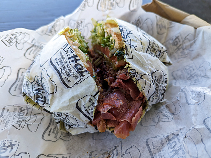 The pastrami sandwich in all its glory—a mountain of thinly-sliced, perfectly seasoned meat that makes other sandwiches look like they're not even trying.