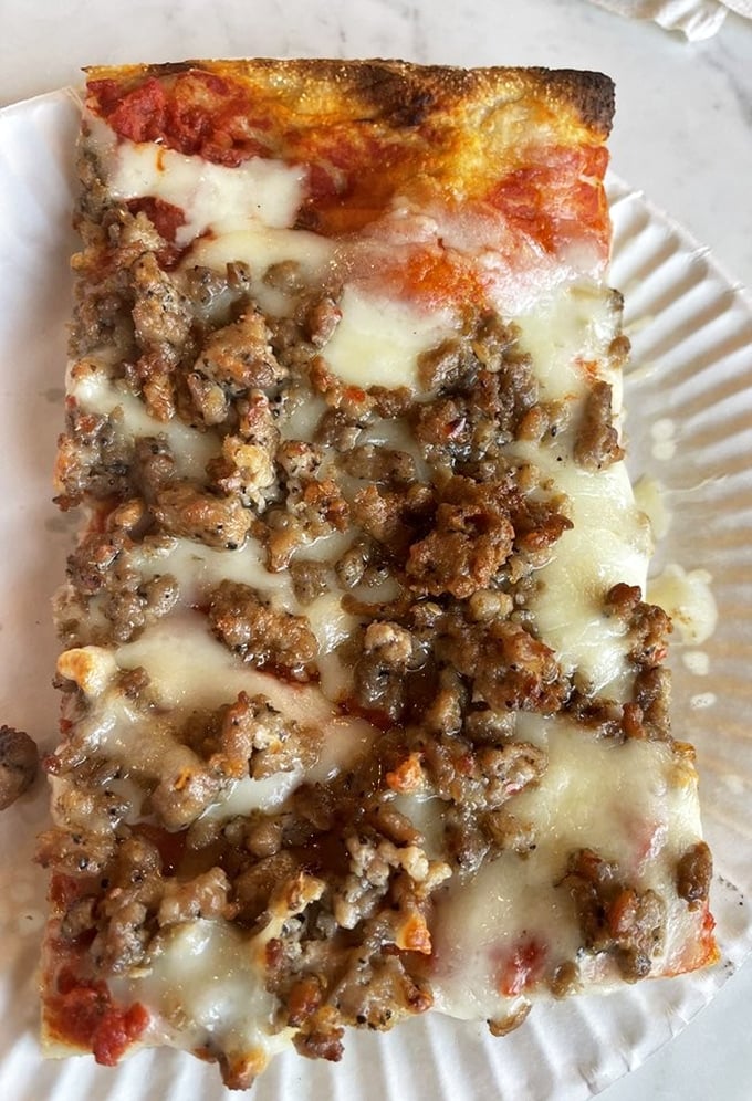 This isn't just pizza—it's a commitment. The sausage-topped slice has that perfect cheese pull that haunts your dreams long after lunch is over.