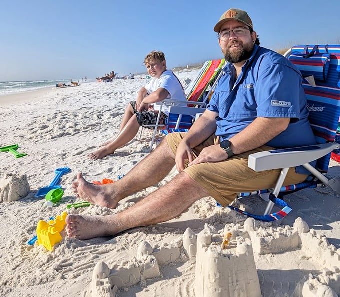 Beach day perfection captured: toes in the sand, castle under construction, and that "I've found paradise" smile that vacation photos were invented for. 