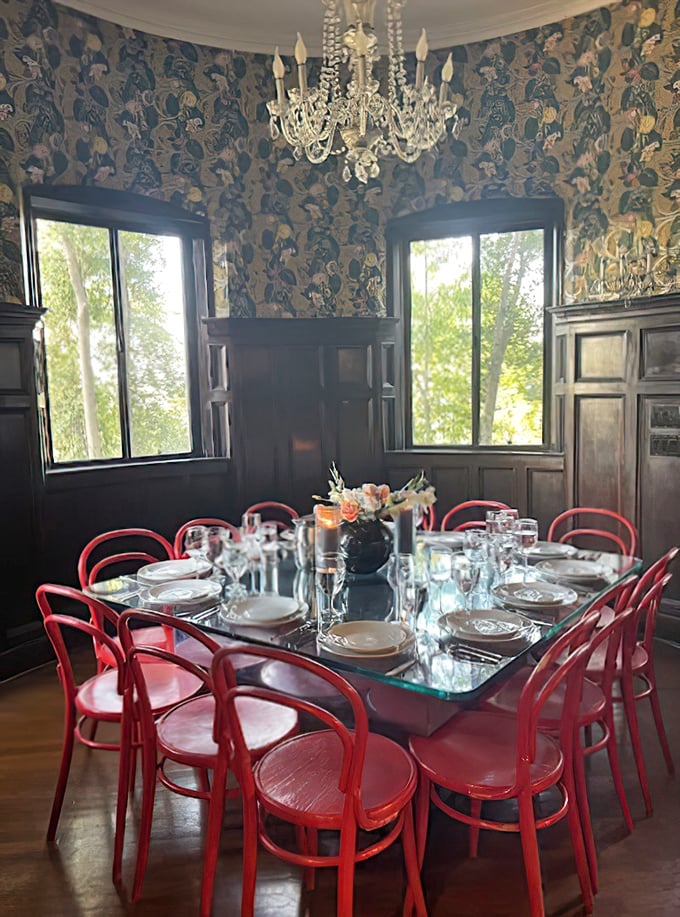 Floral wallpaper meets crystal chandelier in this dining room, where those bold red chairs aren't just making a statement—they're delivering a full-on design TED talk.