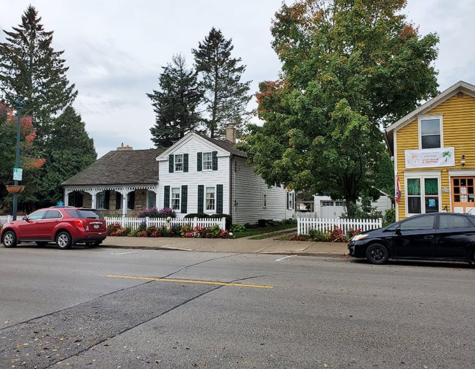 This charming white cottage with its perfect picket fence isn't a movie set—it's someone's actual home, making you wonder if you should check local real estate listings.