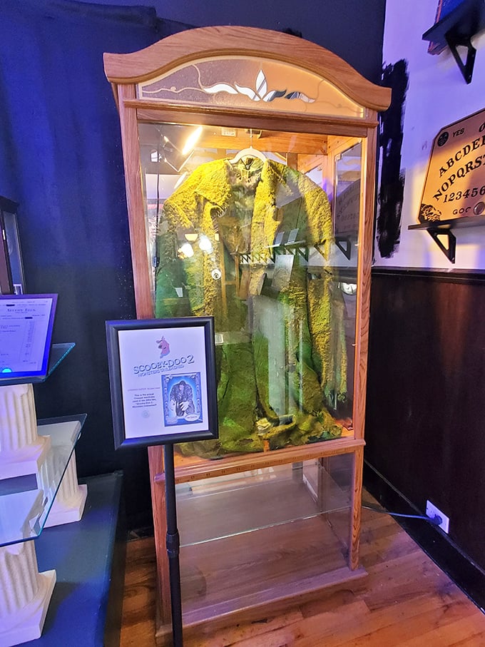 This eerie display case houses what appears to be a ceremonial robe, with a Ouija board visible nearby—communication with the beyond, anyone?