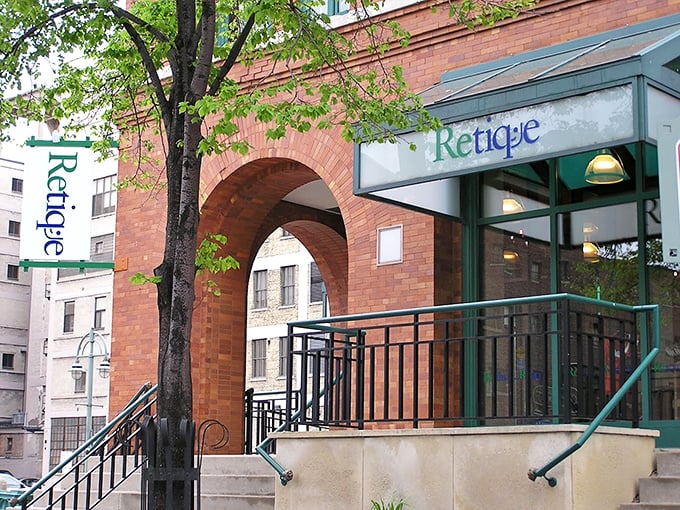 Retique's charming brick archway feels like entering a secret fashion portal. Vintage treasures await behind those green-framed doors.