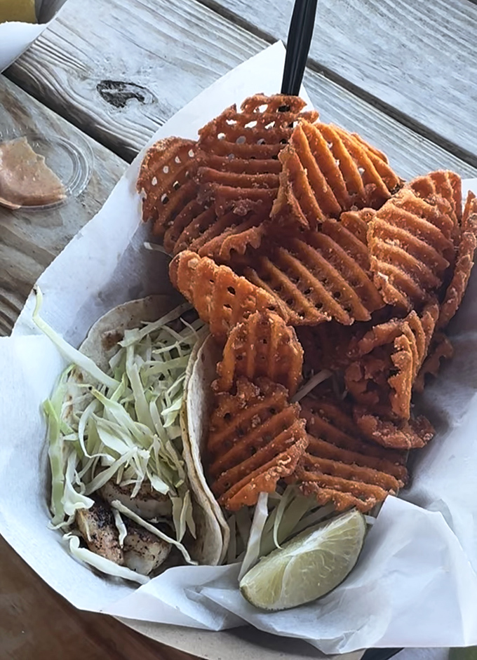 Waffle fries standing guard around a fish taco like crispy sentinels—this is what happens when the ocean and potato patch collaborate brilliantly.