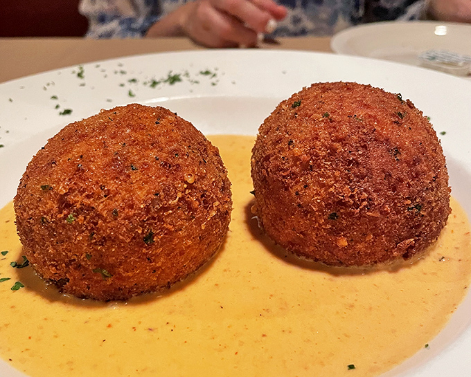 These golden arancini spheres aren't just appetizers; they're crispy orbs of joy swimming in a sea of creamy sauce that whispers, "Resistance is futile."