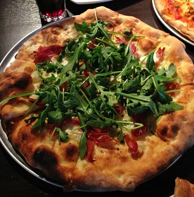 Arugula dancing atop a perfectly charred crust—this isn't just pizza, it's a peppery green celebration on a plate.
