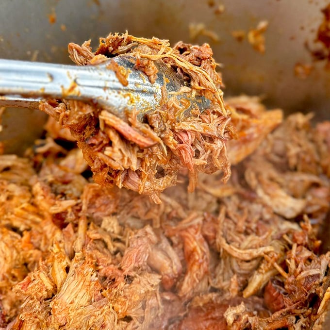 Behold the star of the show – pulled pork so tender it practically surrenders to the tongs, wearing its smoky credentials with pride.
