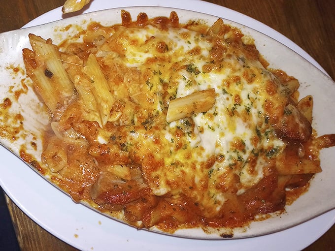 Behold the legendary baked ziti—pasta tubes nestled in rich tomato sauce under a blanket of melted cheese that stretches with each forkful like an Italian tug-of-war.