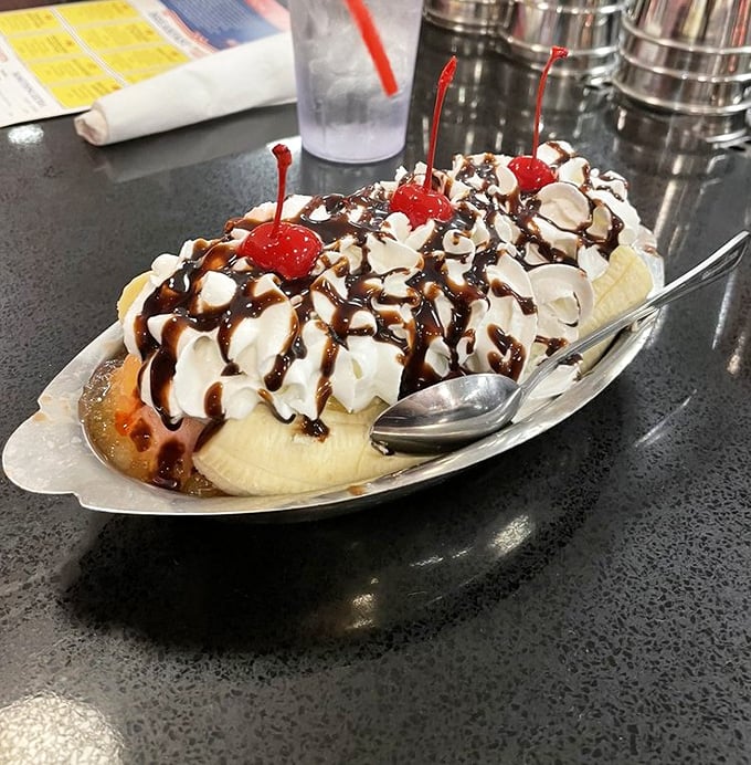 Behold the banana split in all its glory—a yellow canoe navigating rivers of hot fudge, crowned with whipped cream mountains and cherry beacons.