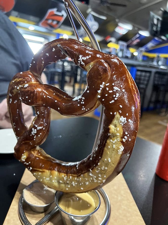 Behold the legendary Bavarian pretzel in all its glory – hanging majestically like edible artwork, with two dipping companions awaiting your decision.