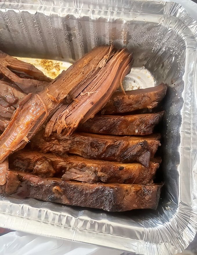 Behold the brisket—bark-crusted, smoke-ringed perfection that pulls apart with just enough resistance to remind you this is serious barbecue business.