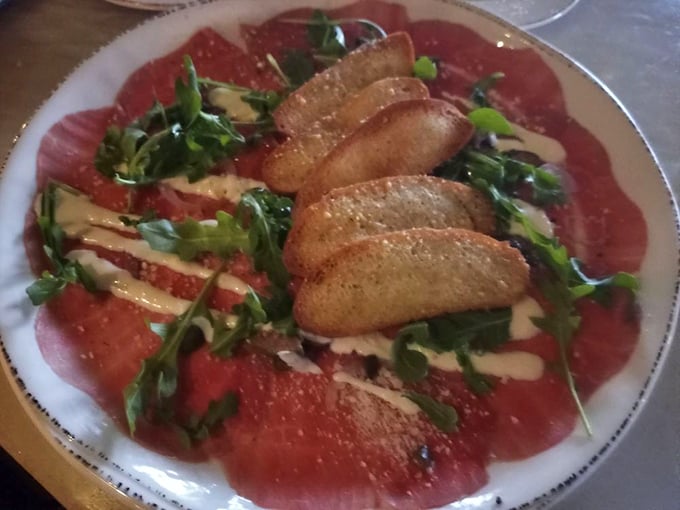 Beef carpaccio that would make an Italian grandmother weep with joy – paper-thin perfection adorned with arugula, crostini, and just the right touch of olive oil.