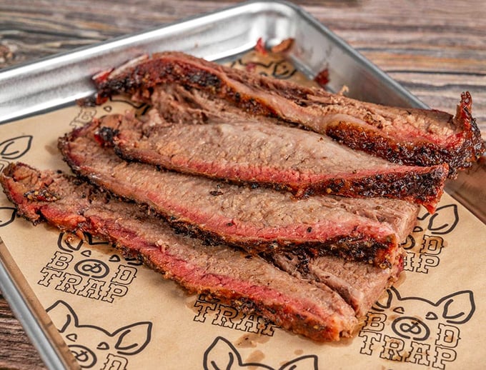 Behold the brisket in all its bark-encrusted glory. Those pink smoke rings aren't just pretty – they're edible badges of honor earned through hours of patient smoking.