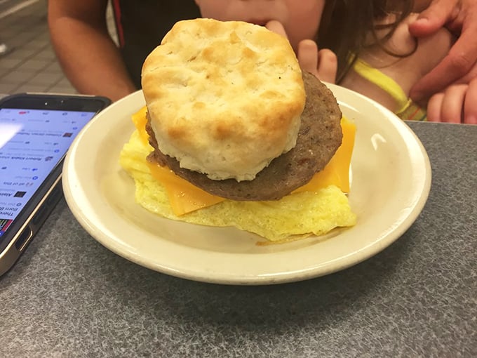 Breakfast architecture at its finest—a golden biscuit, savory sausage, melted cheese, and fluffy egg stacked with the precision of a breakfast Jenga master