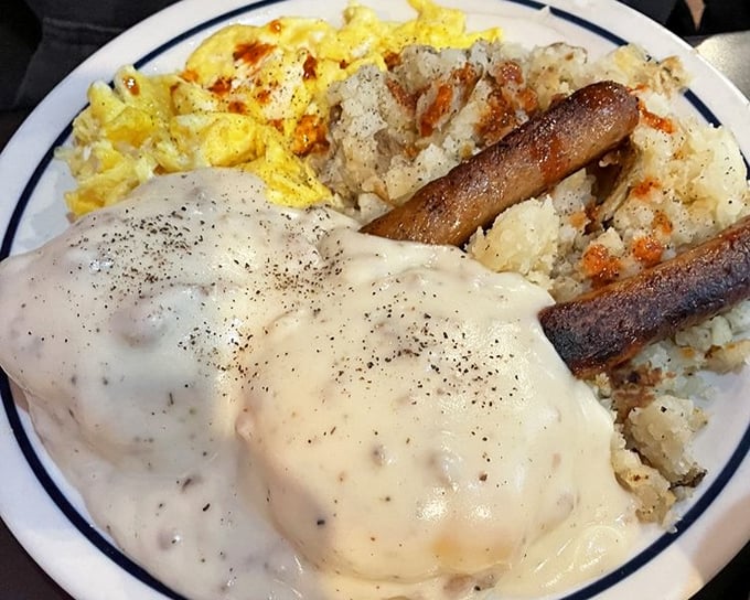Behold the holy grail of comfort food – biscuits drowning in peppery sausage gravy alongside perfectly scrambled eggs and crispy hash browns.