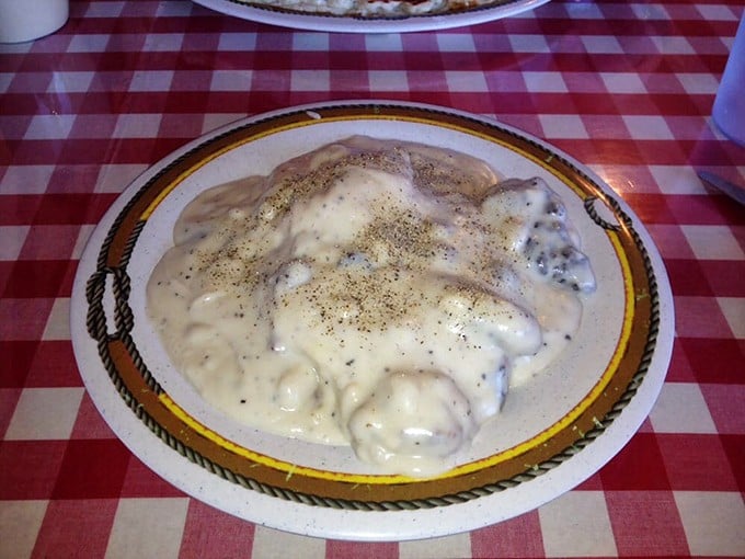This is what breakfast dreams are made of – fluffy biscuits drowning in peppered sausage gravy perfection.