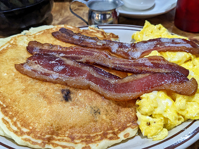 Breakfast perfection on a plate – golden pancakes with perfectly crisp edges, fluffy scrambled eggs, and bacon cooked to that magical point between chewy and crisp.